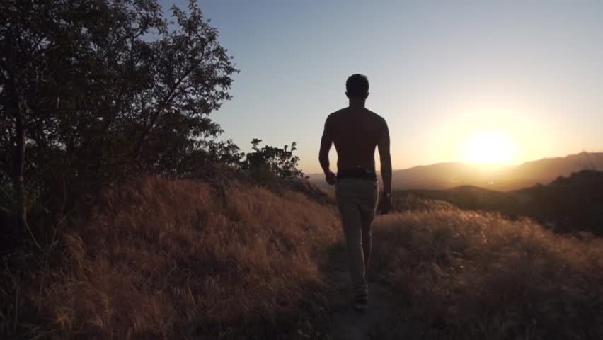 A Man Walks Away From The Camera In A Rocky And Barren Desert Wasteland ...