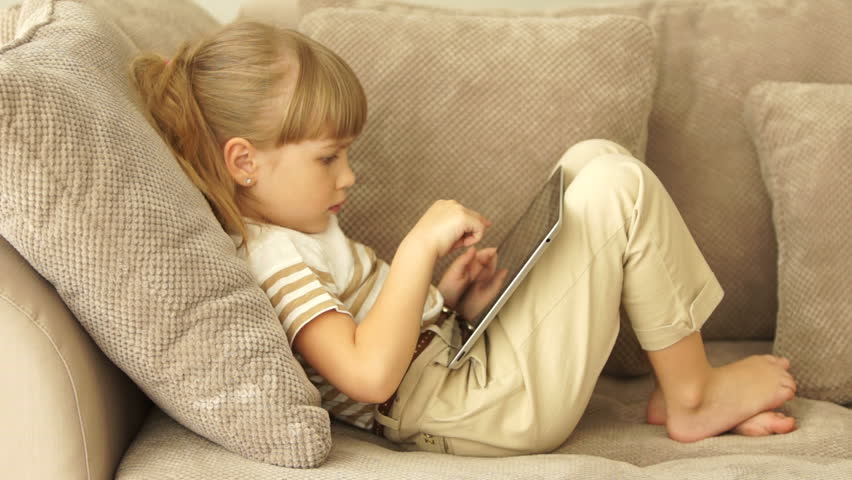A Cute Little Baby Boy Watching A Movie On An IPad Tablet In The Living ...
